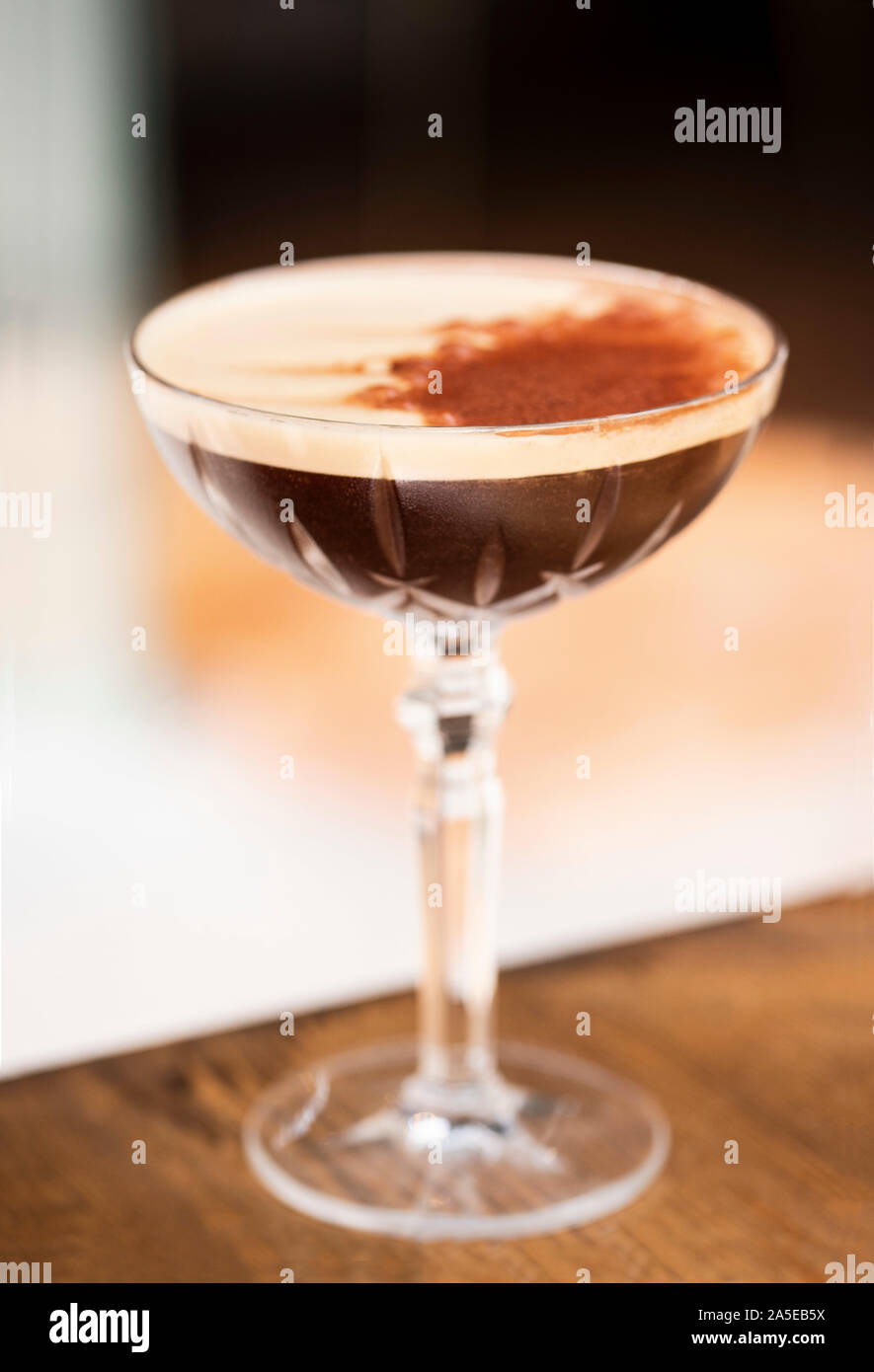Dark cocktail espresso martini decorated with cacao on wooden surface ...
