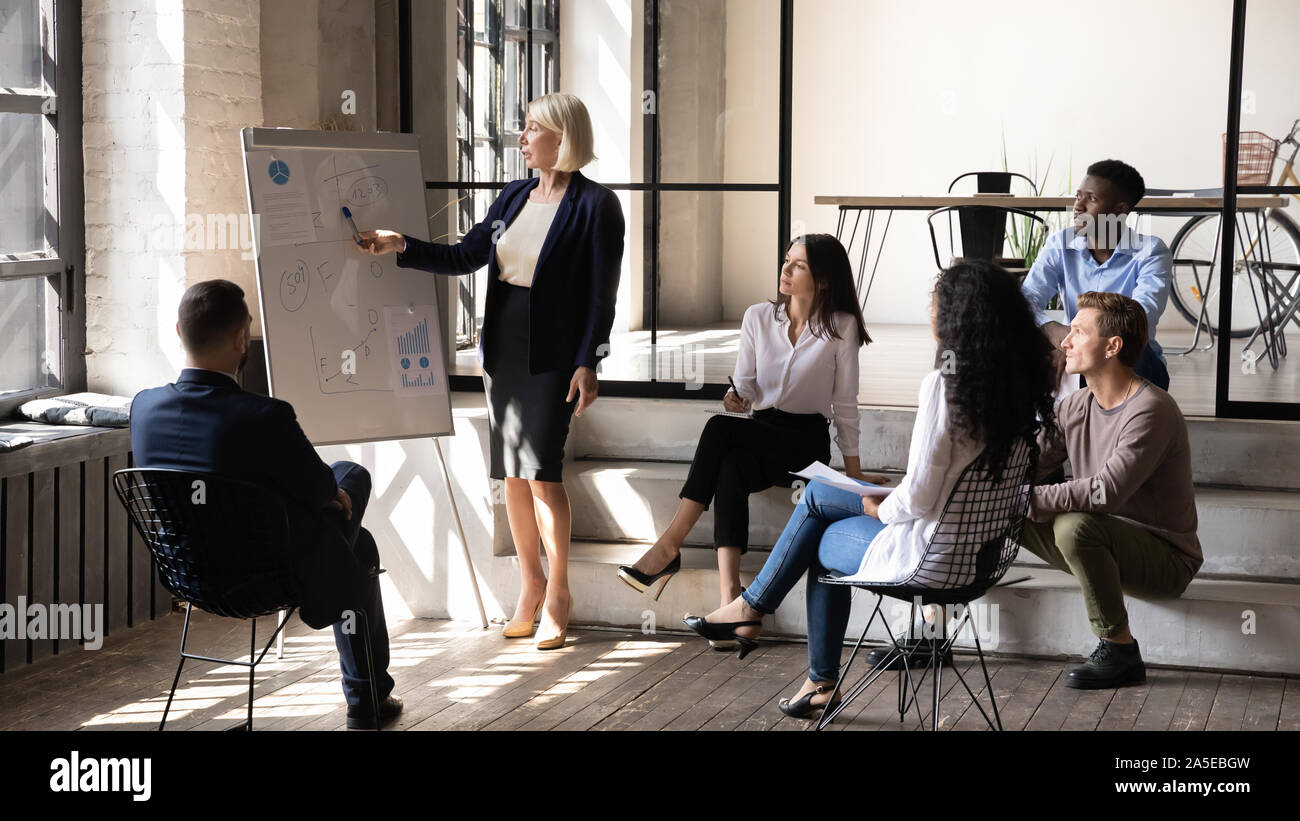 Serious middle aged businesswoman mentor give presentation in office ...