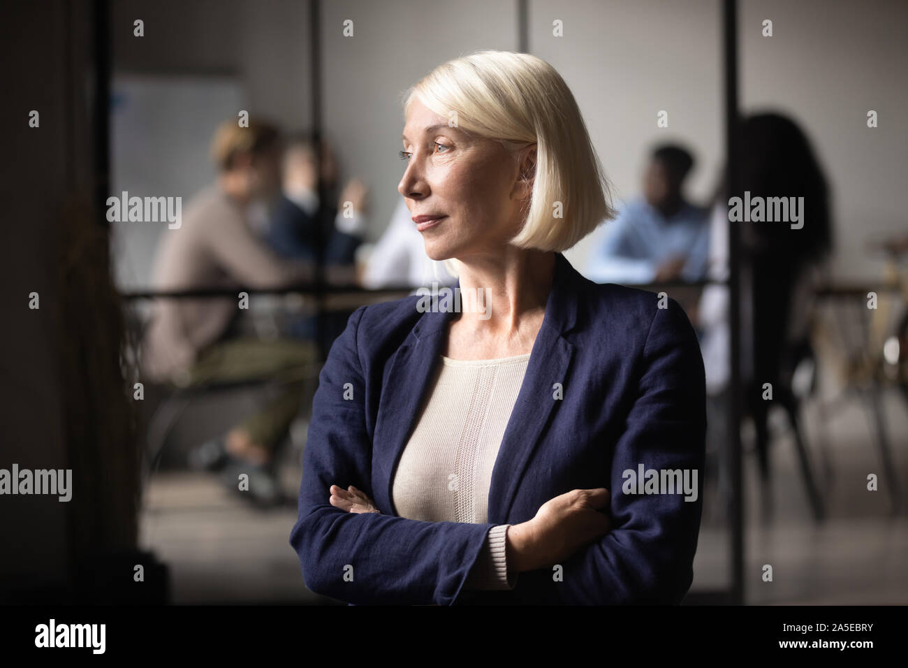 Thoughtful old businesswoman ceo looking through window thinking of ...