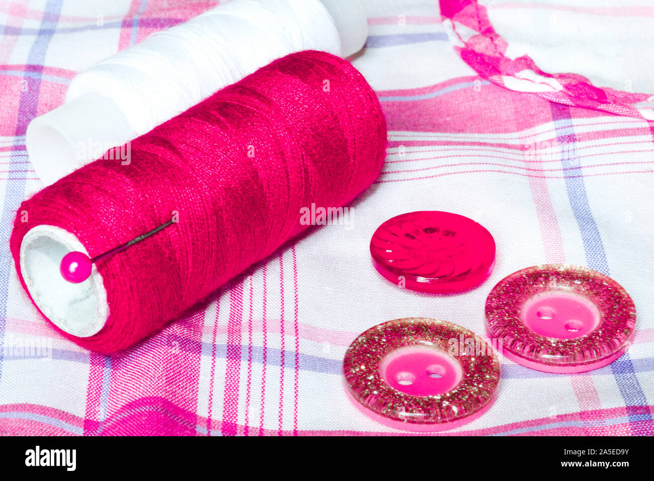 Red and white thread and buttons on a checkered cloth. Sewing ...
