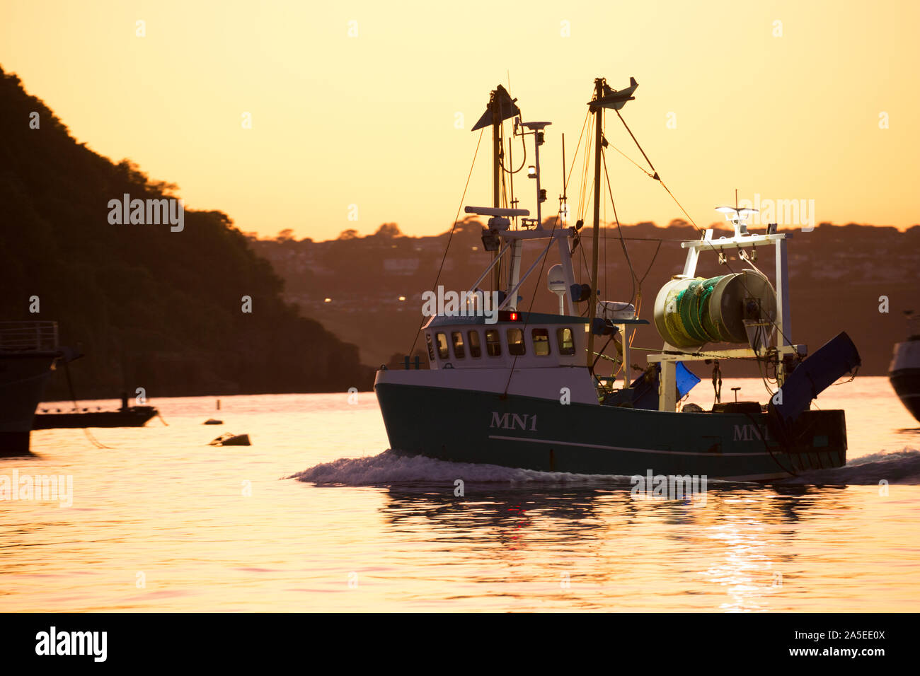 A fishing boat entering the outer harbour of Brixham Port as the sun ...