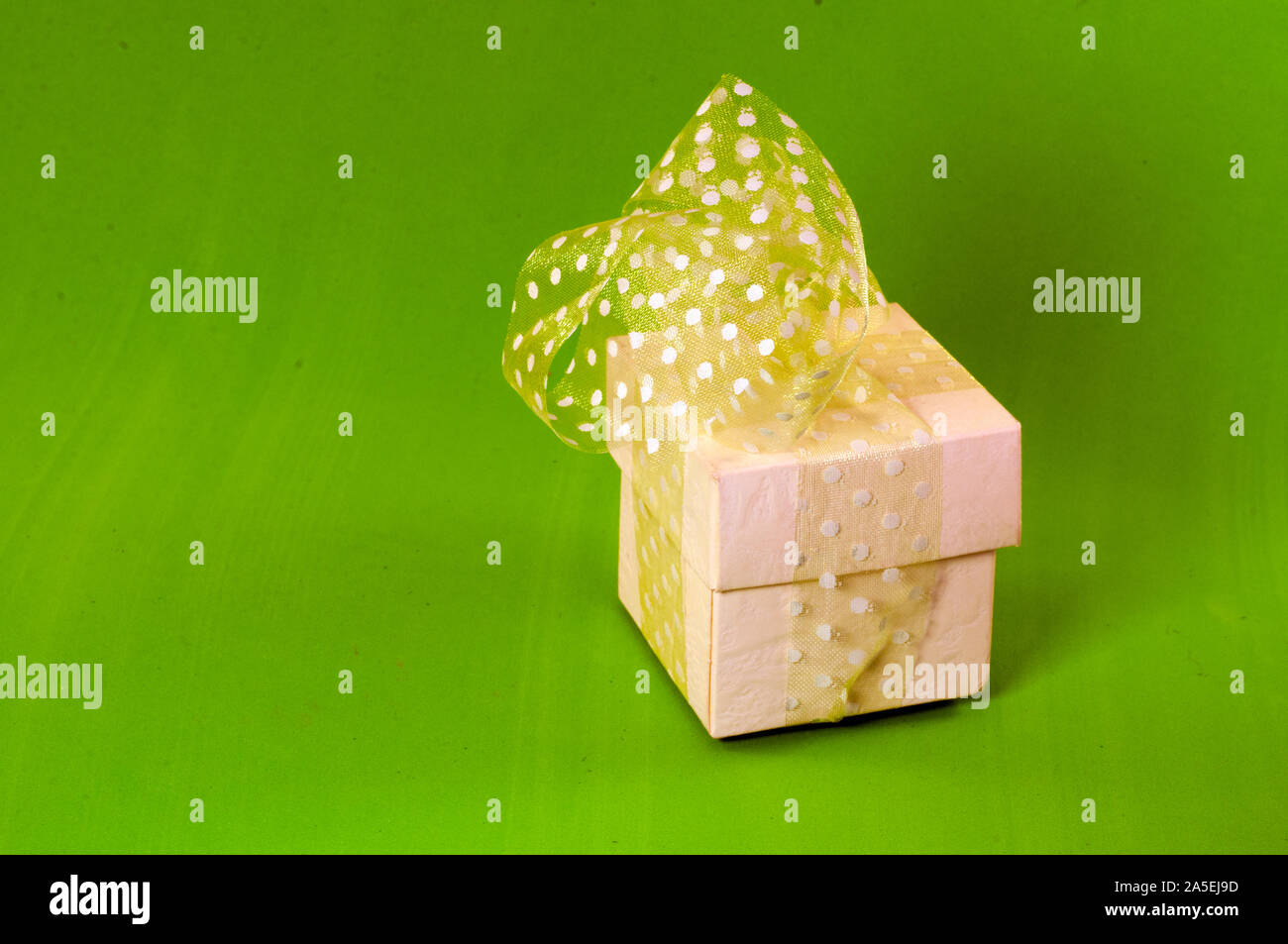 Isolated single gift box with green ribbon with white spots on green ...