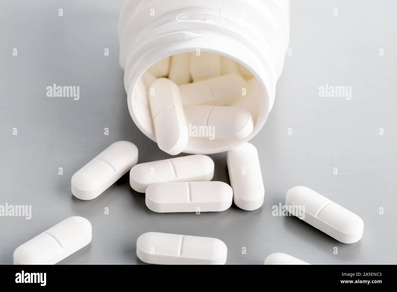 White drugs scattered in front of plastic bottle of pills Stock Photo ...