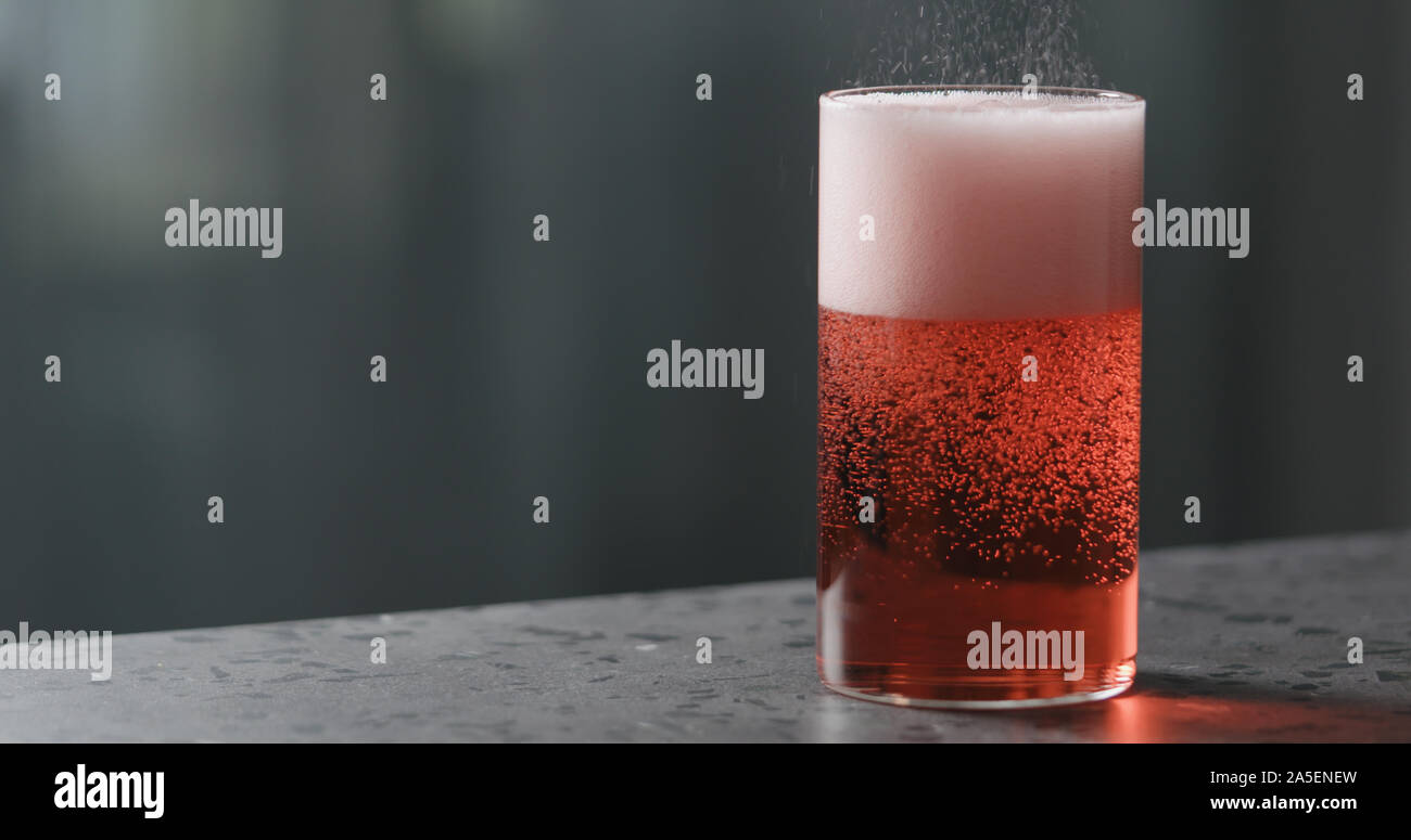 pour berry cider into glass on terrazzo countertop with copy space ...