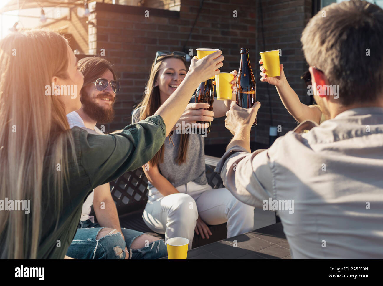 Jolly friends drinking beer during Friday evening party on a loft ...