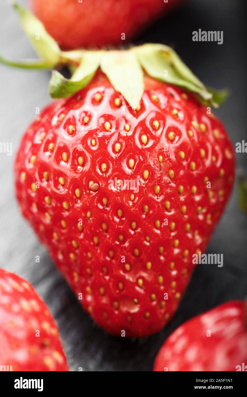 ripe strawberries scattered on a black slate background. bright red ...