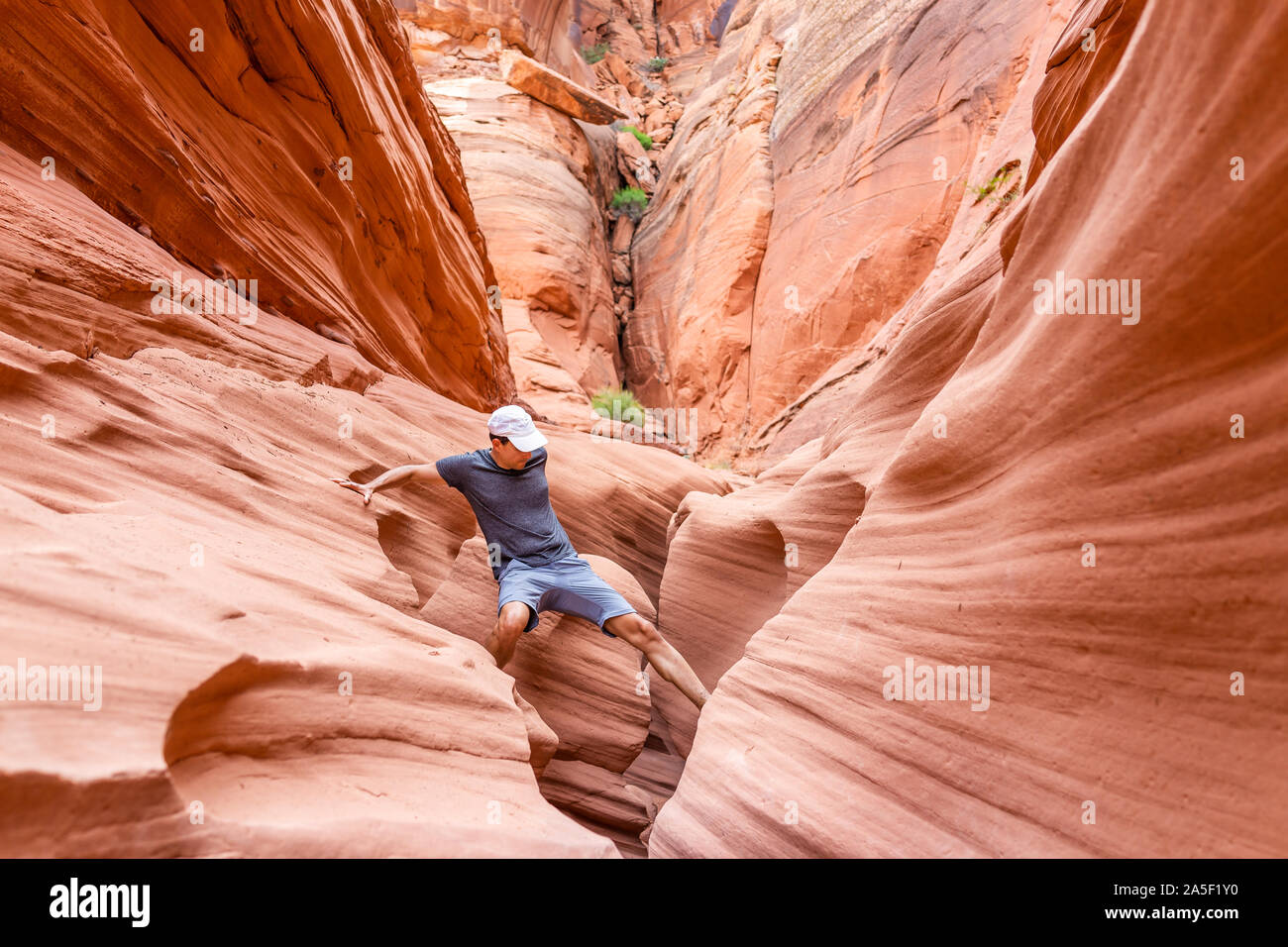 Orange red wave sandstone formations and man climbing crossing rocks at ...