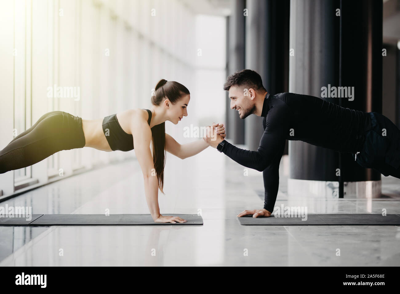 Young sporty couple working out together in a gym . Doing plank ...