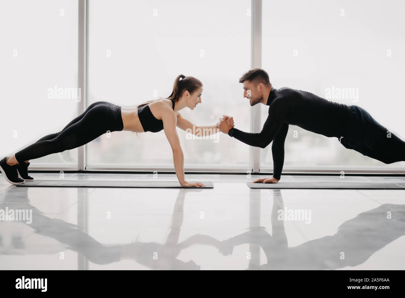 Young sporty couple working out together in a gym . Doing plank ...
