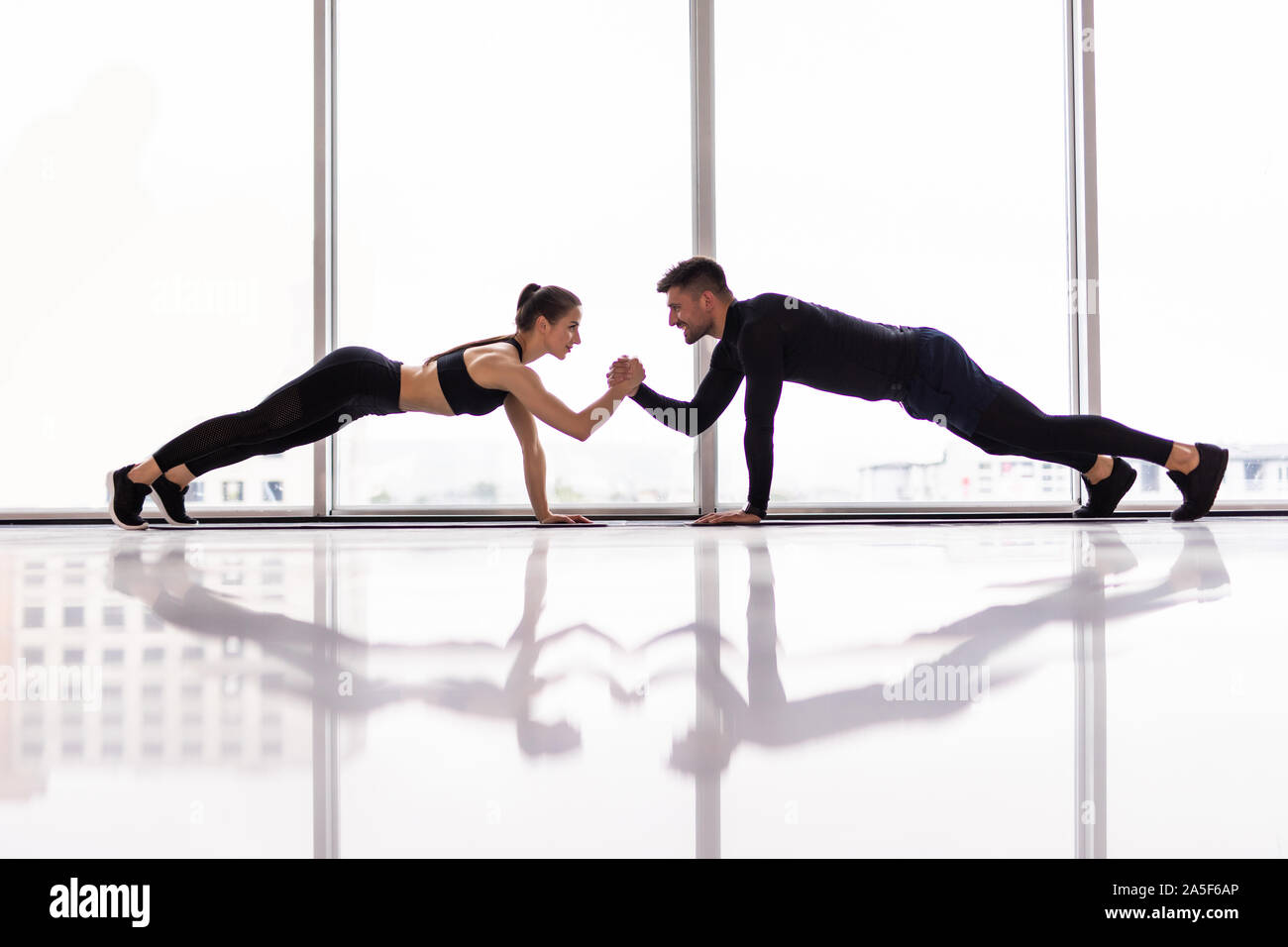 Young sporty couple working out together in a gym . Doing plank ...