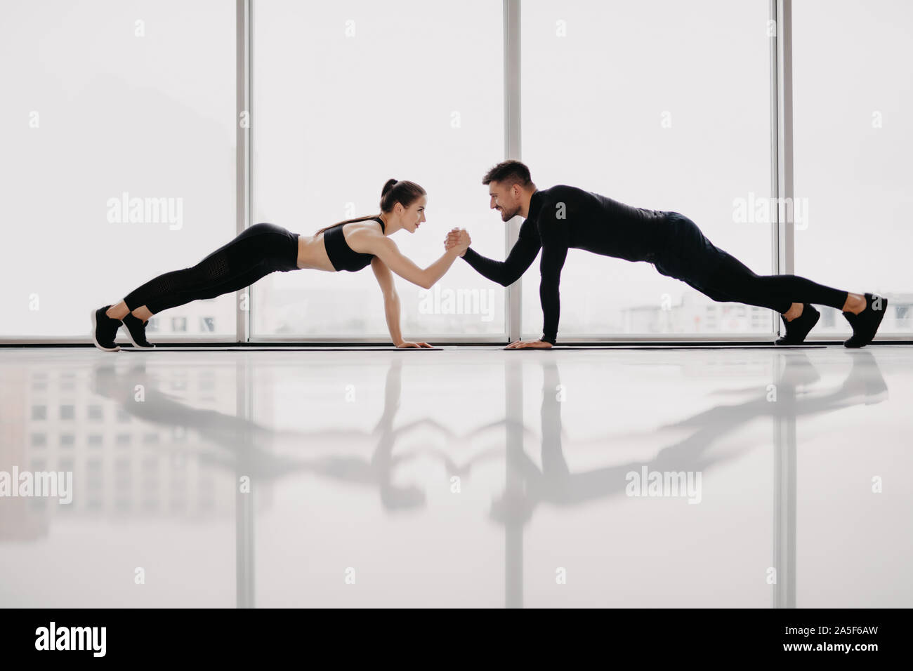 Two people that love fitness are standing on one hand in plank position ...