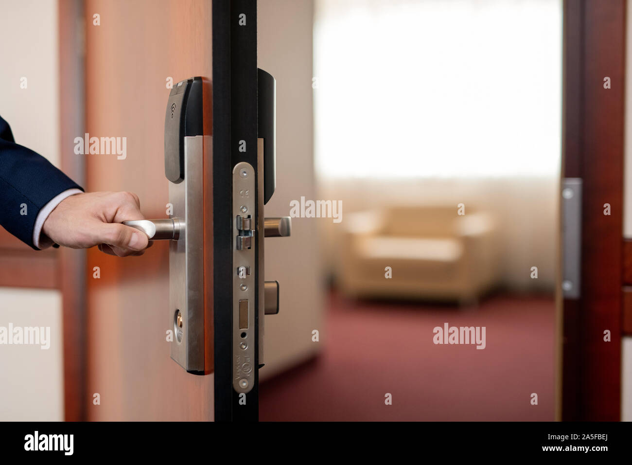 Human hand holding handle of wooden door while entering one of hotel ...