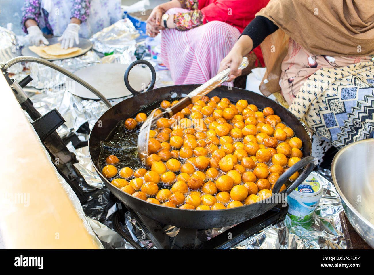 A woman sitting and cooking Traditional sweets of the Arab world Lokma ...