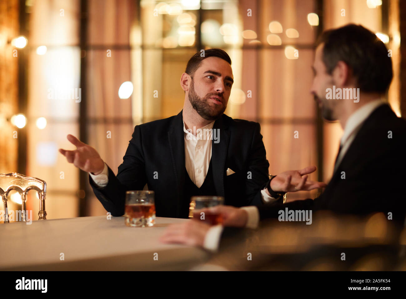 Portrait of two business people talking while sitting at table in ...