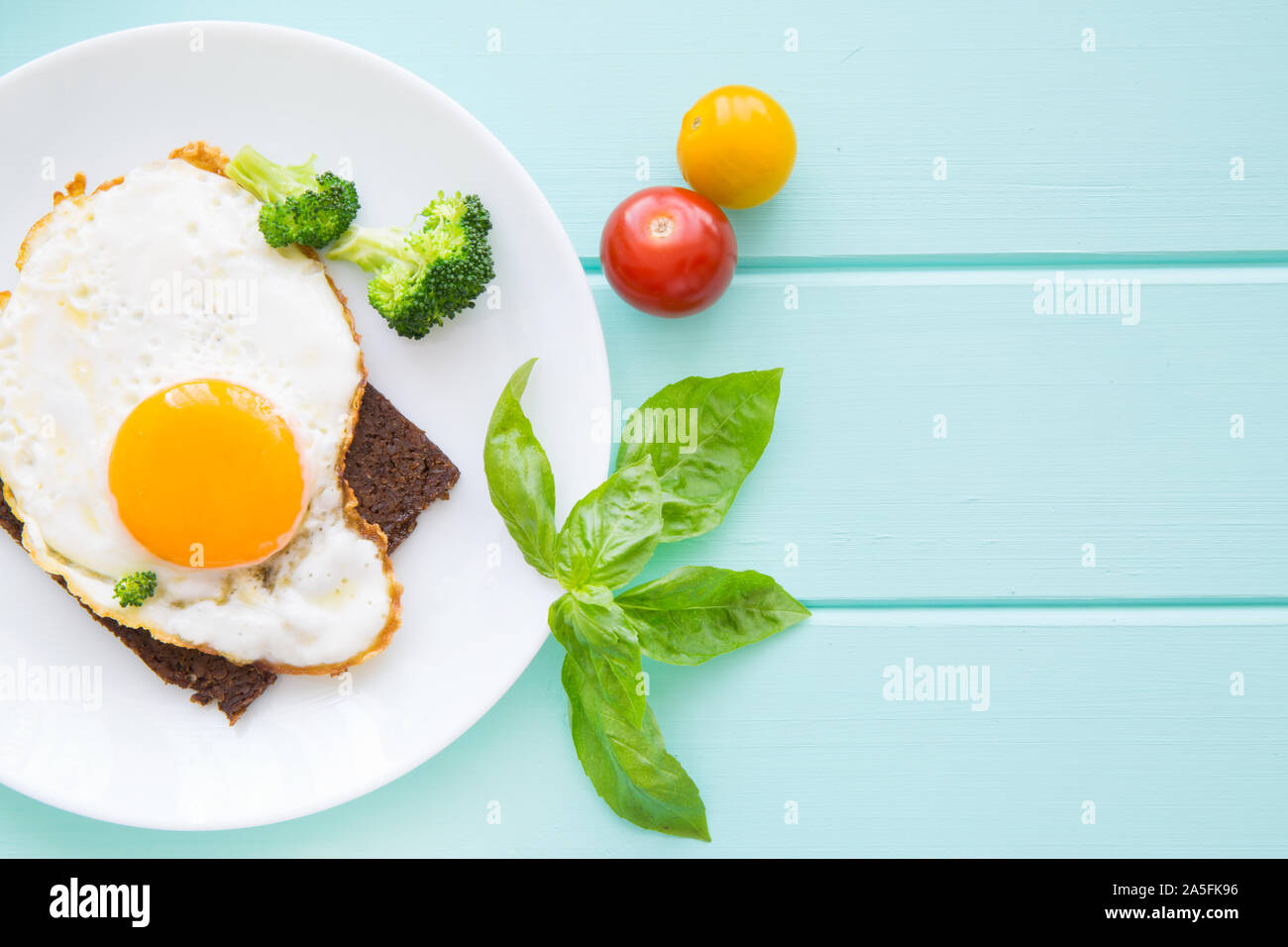 Rye bread toasts with fried eggs and vegetables: cherry tomatoes ...