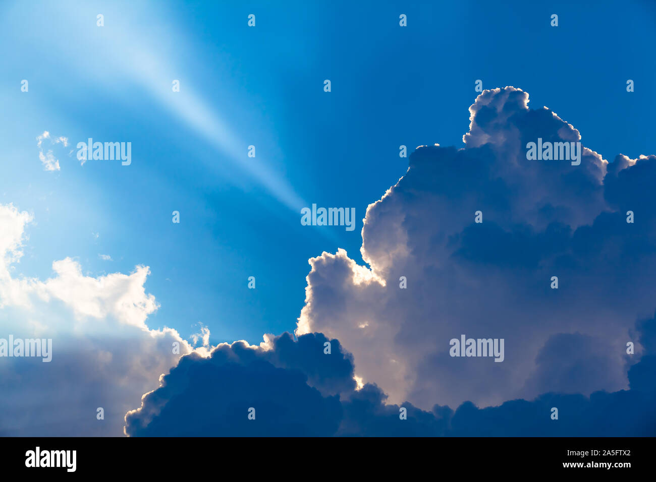 Small ray of sunlight up to blue sky behind dark clouds (copy space ...