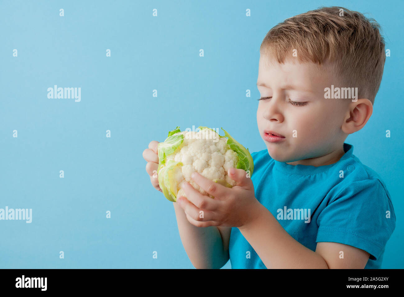 Little Boy Holding Broccoli in his hands on blue background, diet and ...