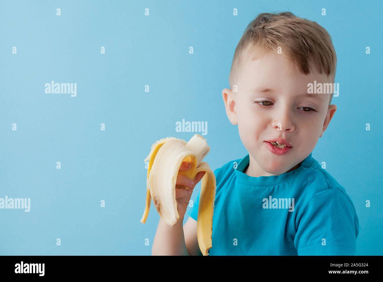 Little Boy Holding and eating an Banana on blue background, food, diet ...