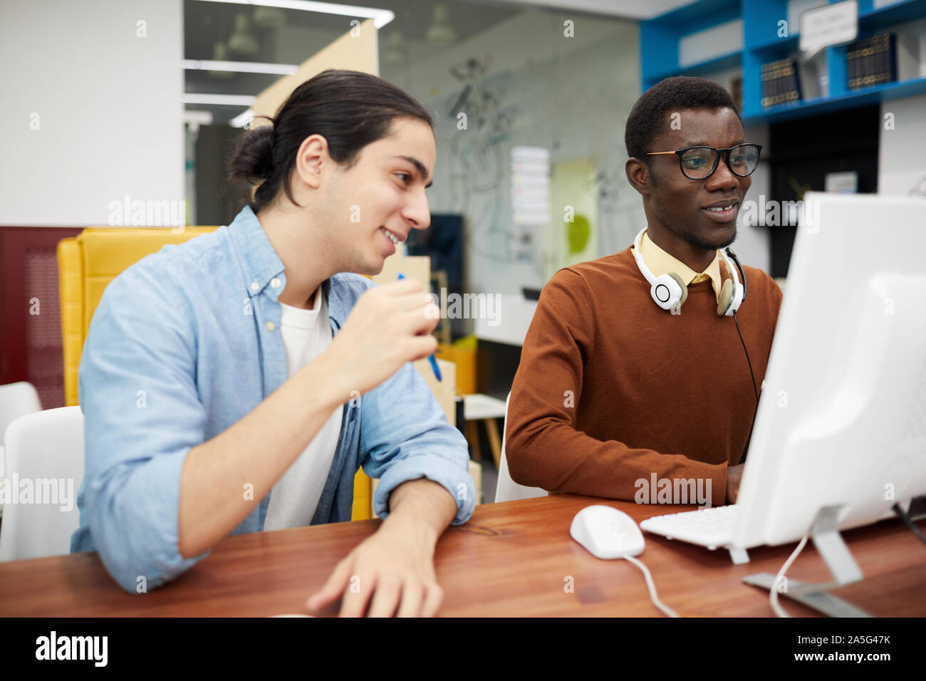 Portrait of two smiling college students using computer while ...
