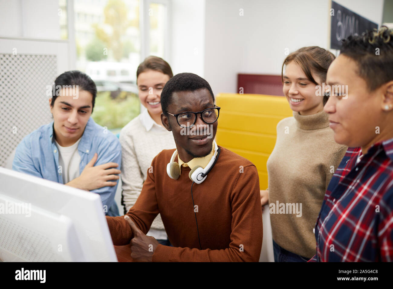Portrait of multi-ethnic group of students using computer while ...