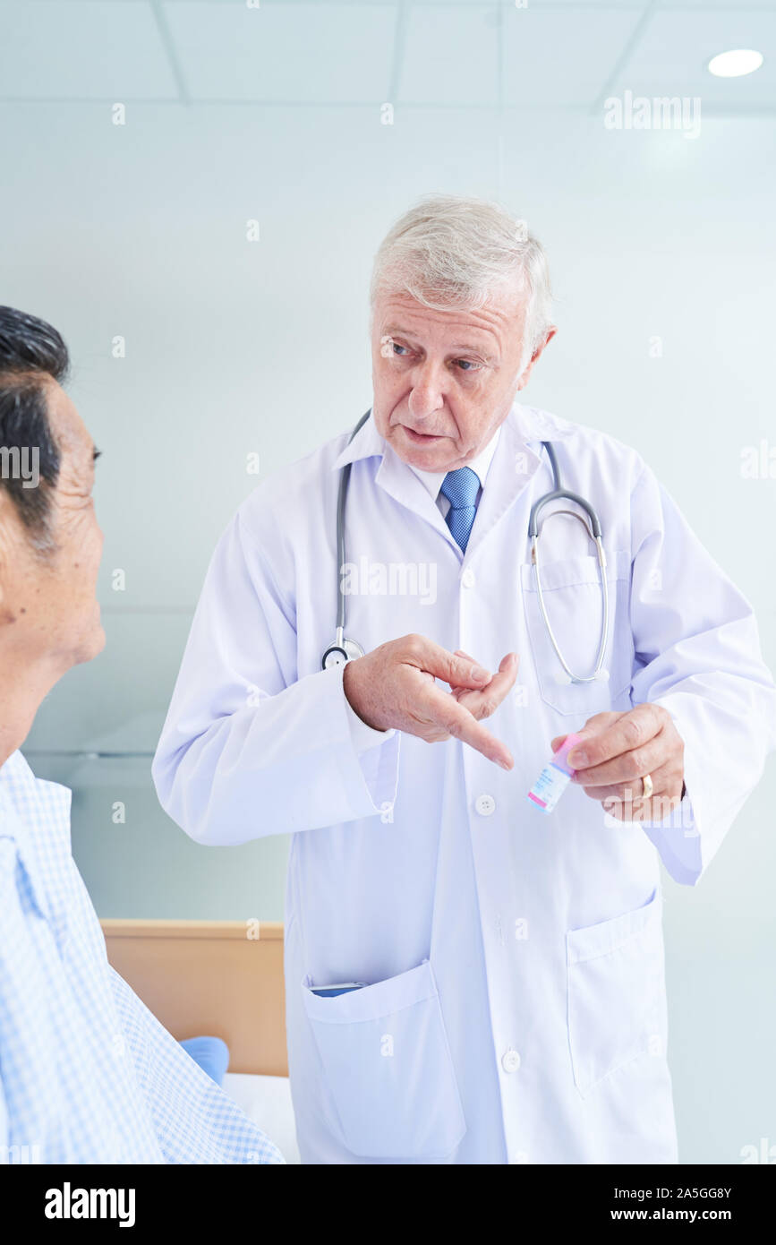 Experienced general practitioner giving bottle of medicine to senior ...