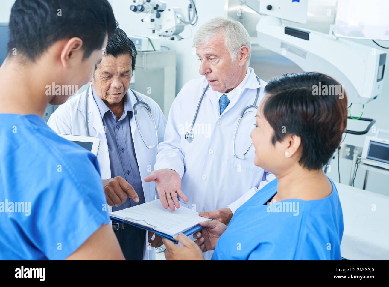 Group of doctors meeting in operating theater and discussing documents ...