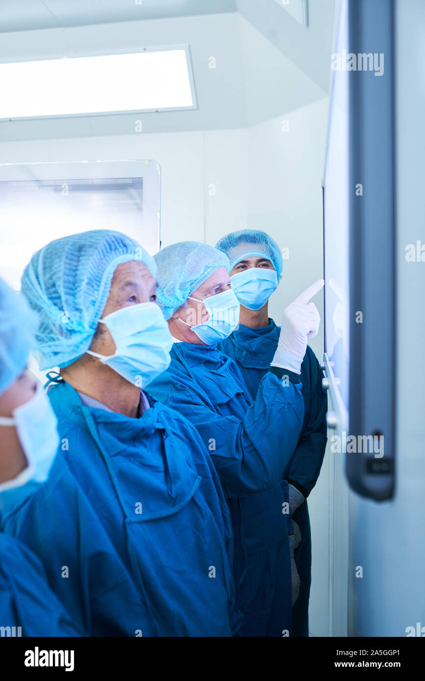 Surgeons reading medical history of patient and checking results of his ...