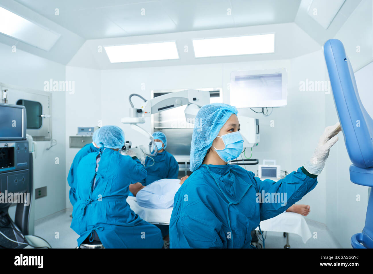 Asian nurse in scrubs setting program on computer for surgical ...