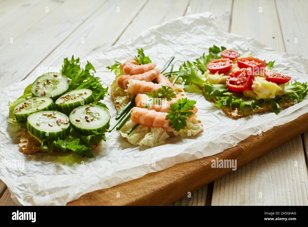 Slices of waffle bread with different vegetables, shrimp and seasoning ...