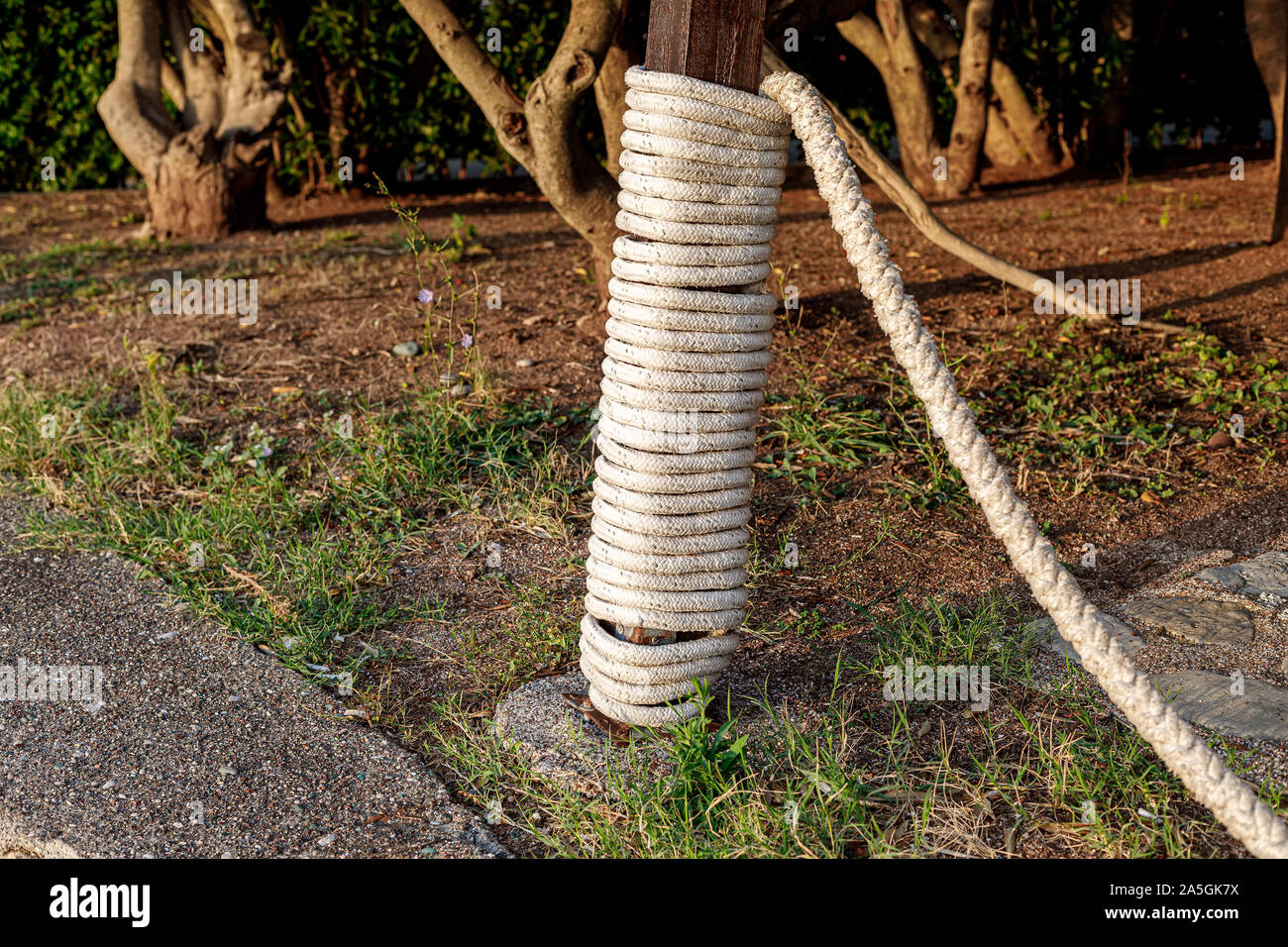 Post or pole with rope coiled around it. Green grass background Stock ...