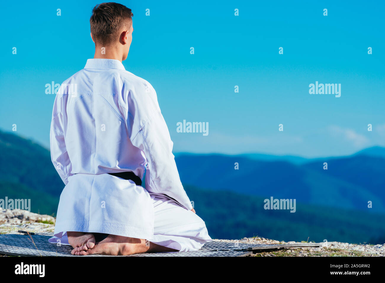Karate master meditating on top of a mountain wearing kimono while ...
