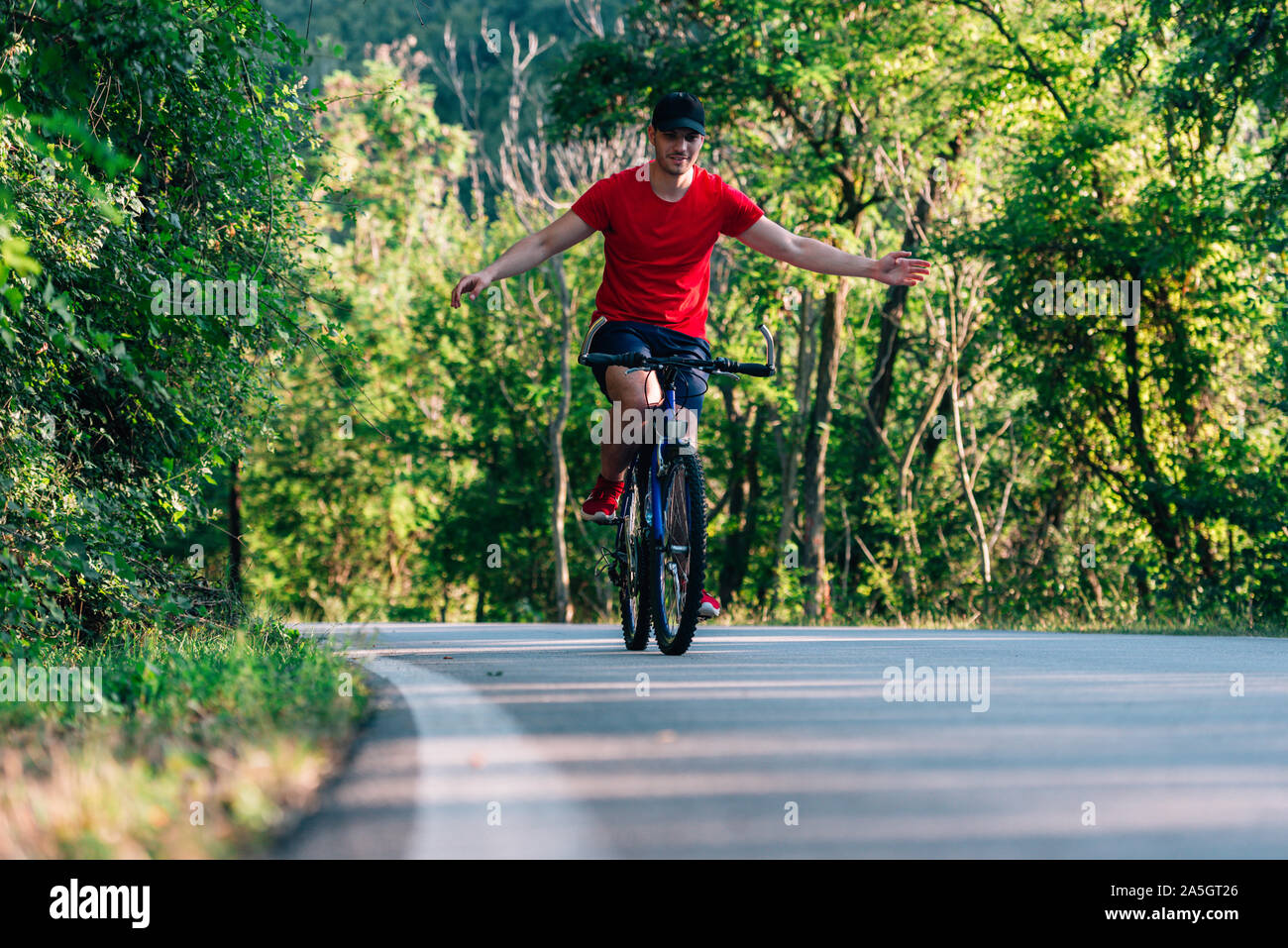 Happy biker cyclist riding his bike through the green woods Stock Photo ...