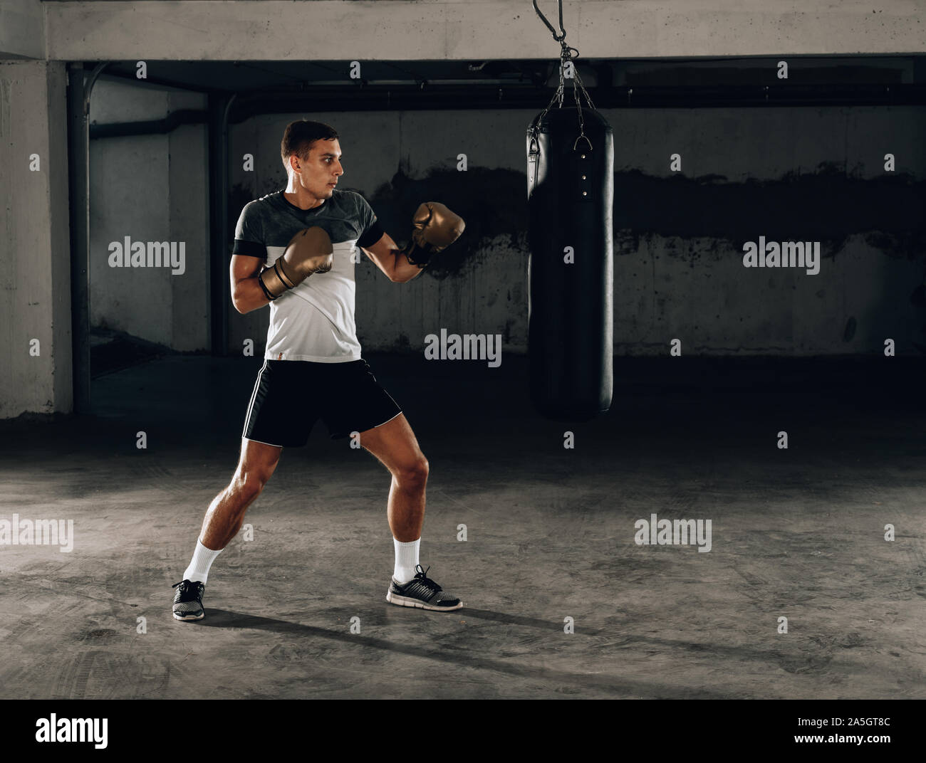 Muscular handsome fighter giving a forceful forward kick during a ...