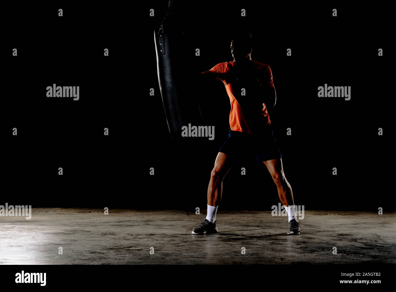 Young man athlete boxing workout in fitness gym on dark background ...