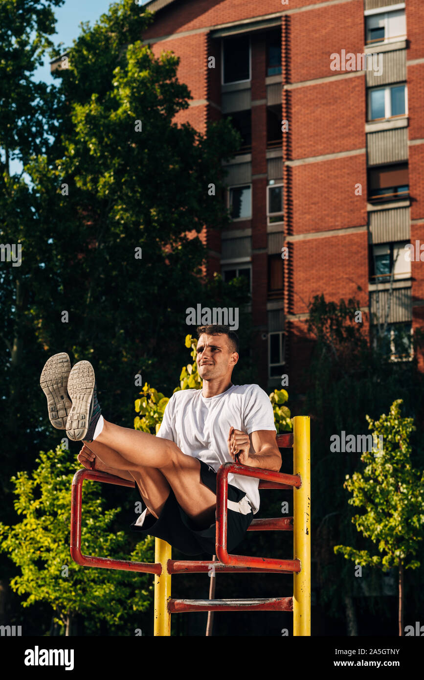 Young muscular build man doing dips exercises on horizontal bar ...