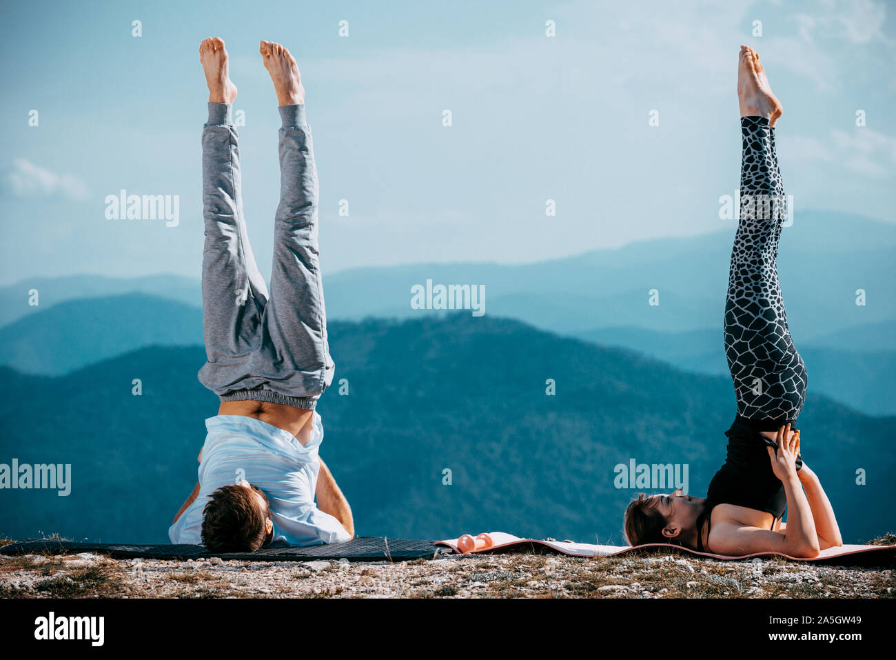 Yoga at summit with aerial view of the mountain range and peak. Blue ...