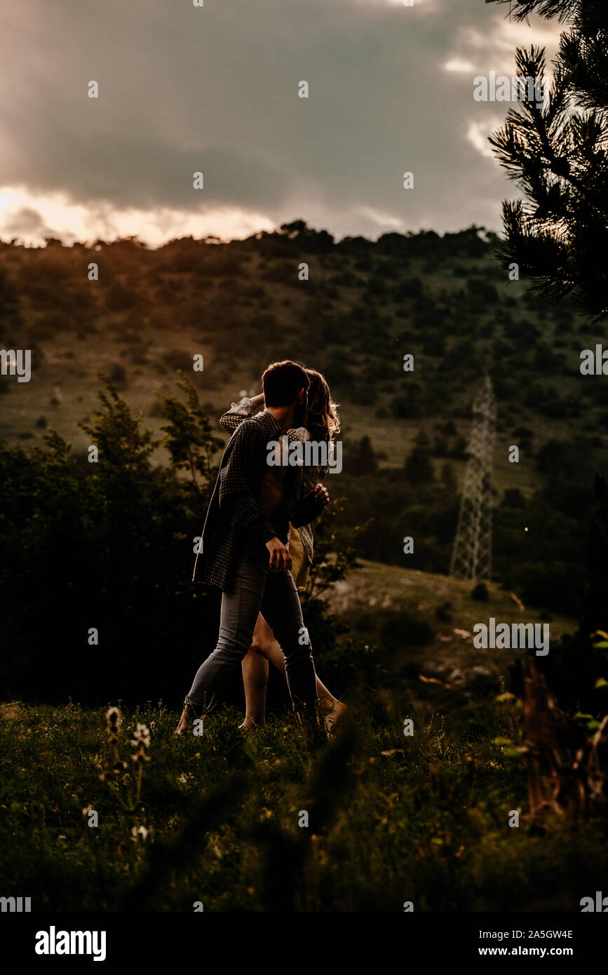 Romantic young loving couple dancing outdoors under orange sky at ...