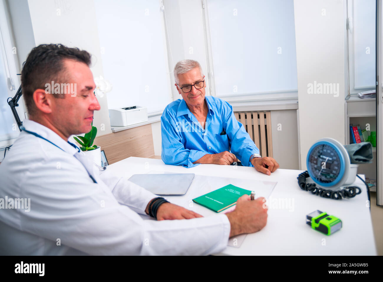 Serious middle aged doctor prescribes his senior patient the medication ...