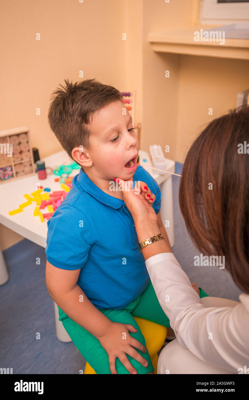 Female Pediatrician check's the throat and mouth of a young cute boy ...