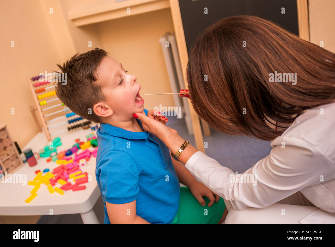 Female Pediatrician check's the throat and mouth of a young cute boy ...