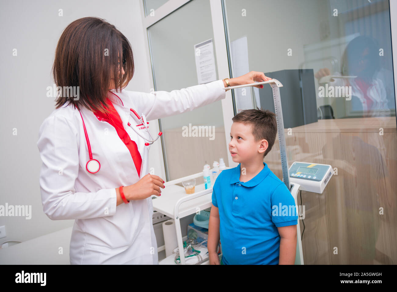 Female doctor measuring the height of little boy in a clinic ( hospital ...