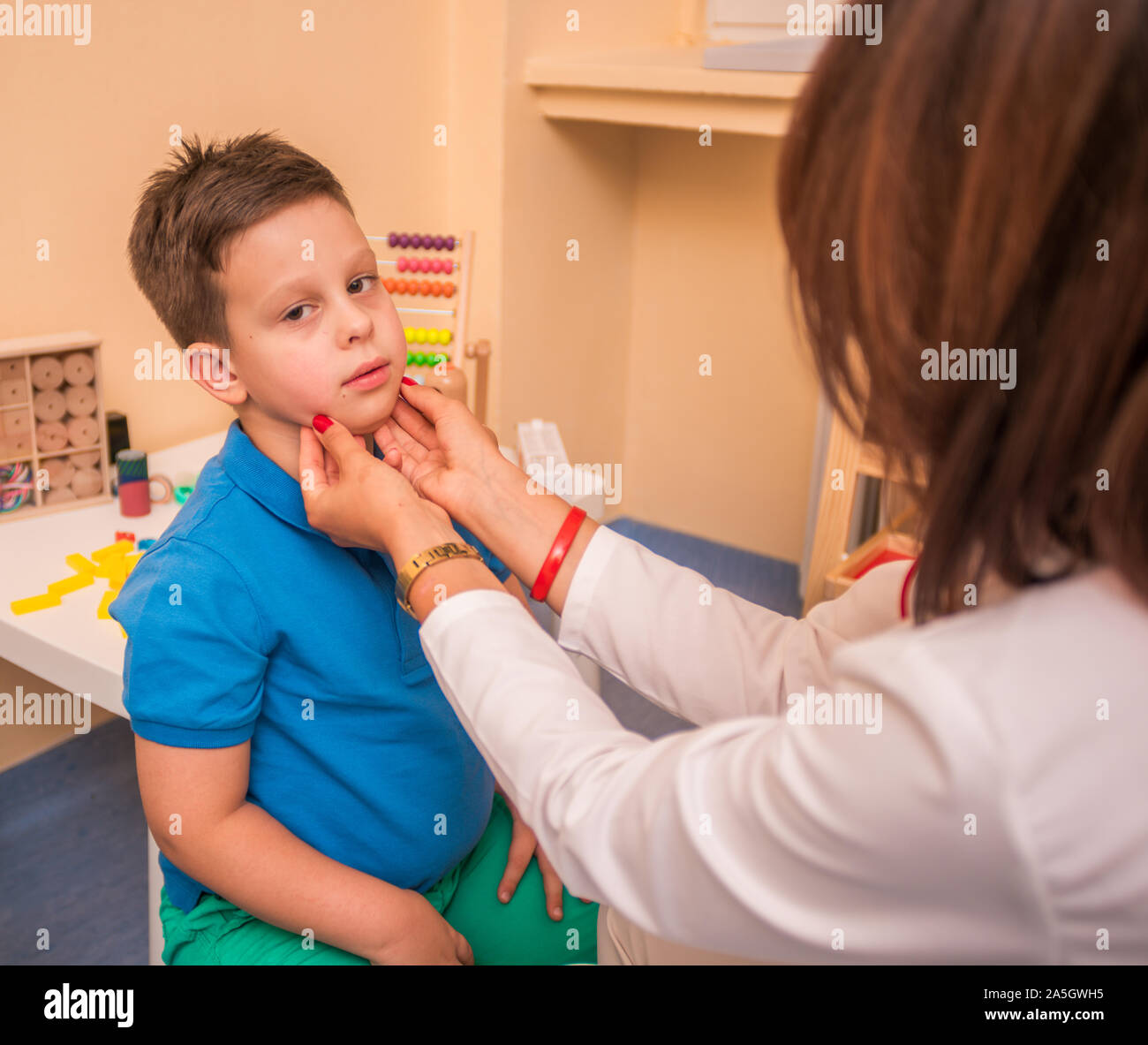 Female Pediatrician check's the throat and mouth of a young cute boy ...