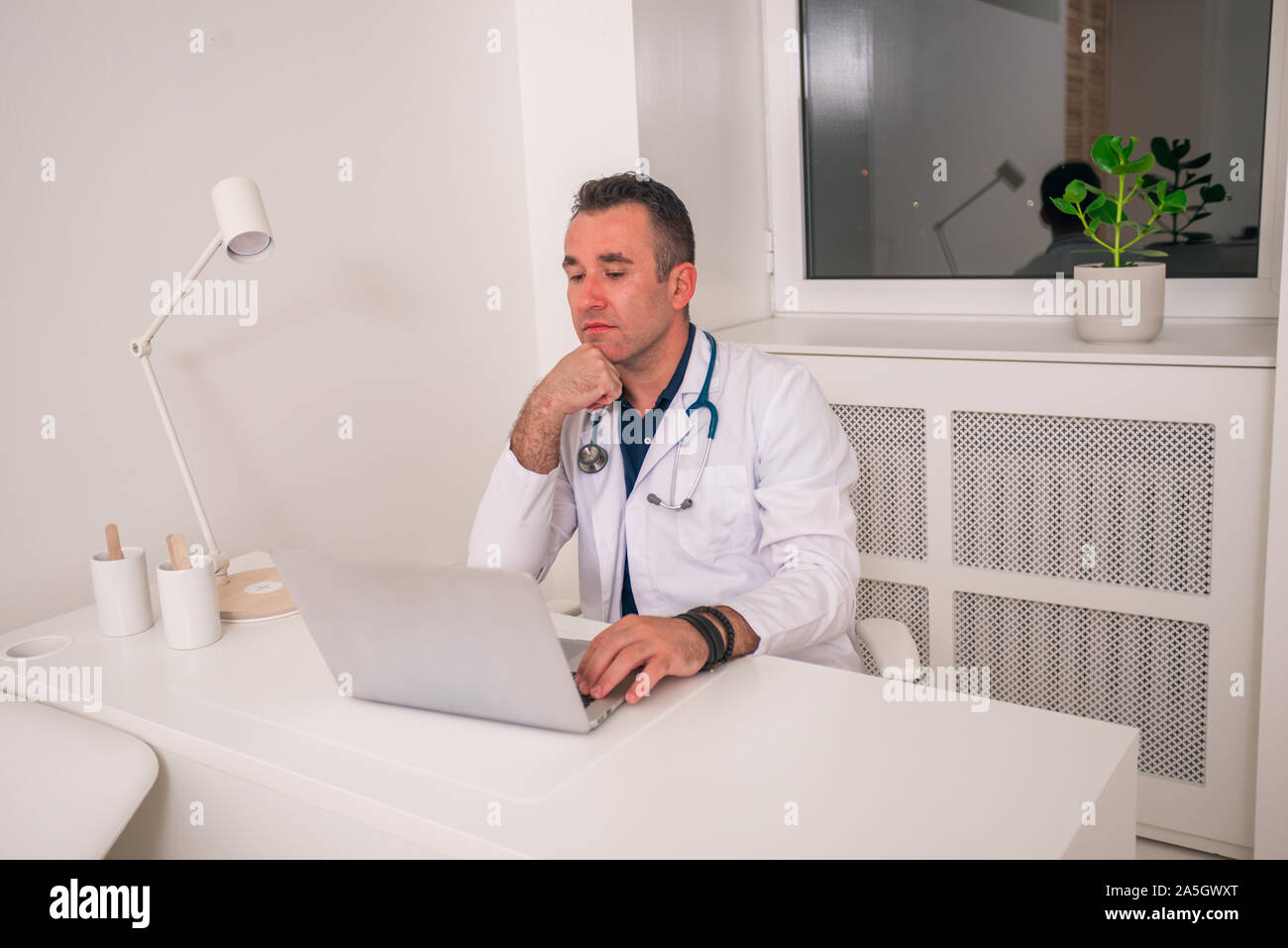 Portrait of Doctor specialist sitting on a chair at his desk while ...