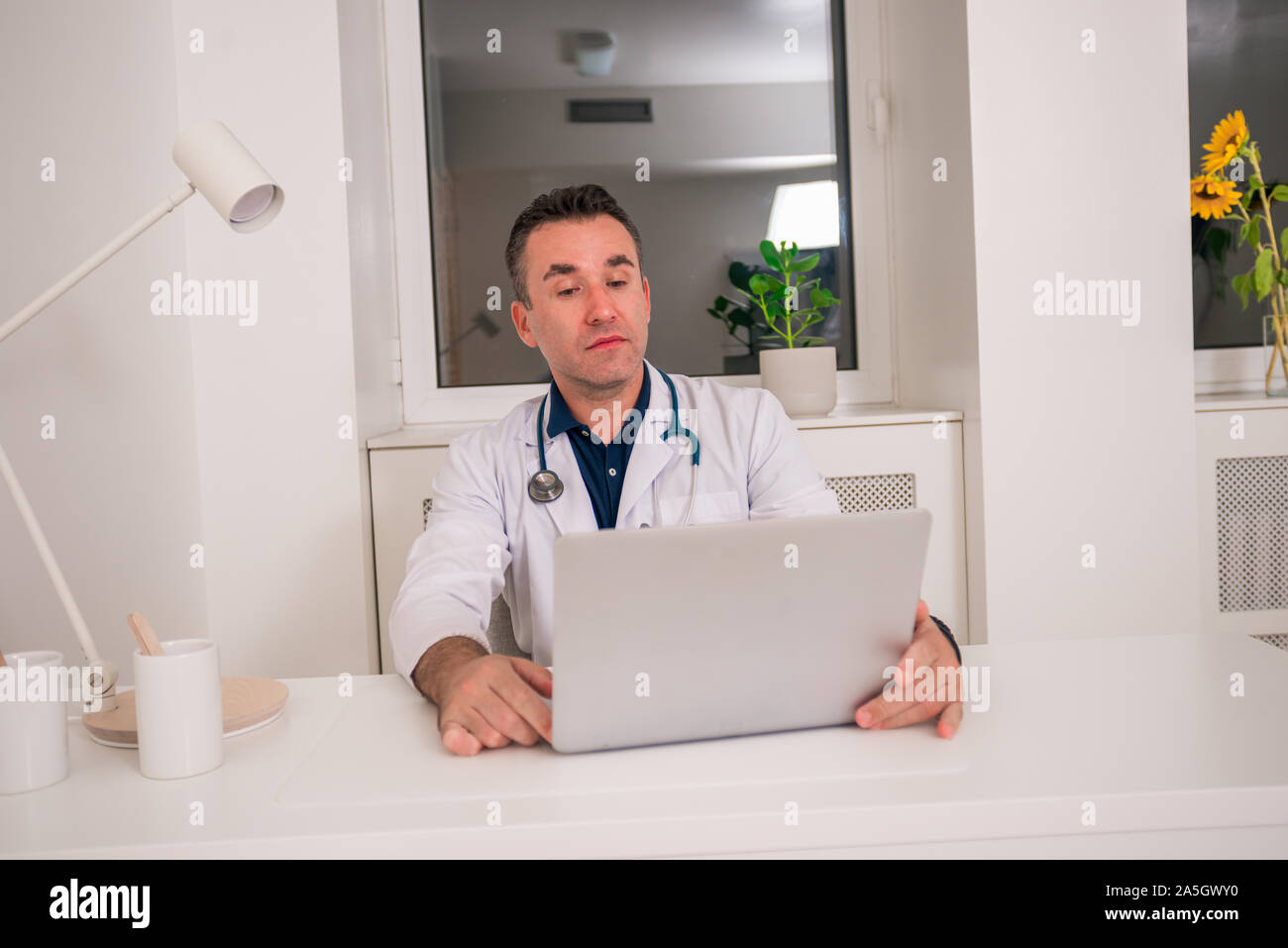 Portrait of Doctor specialist sitting on a chair at his desk while ...