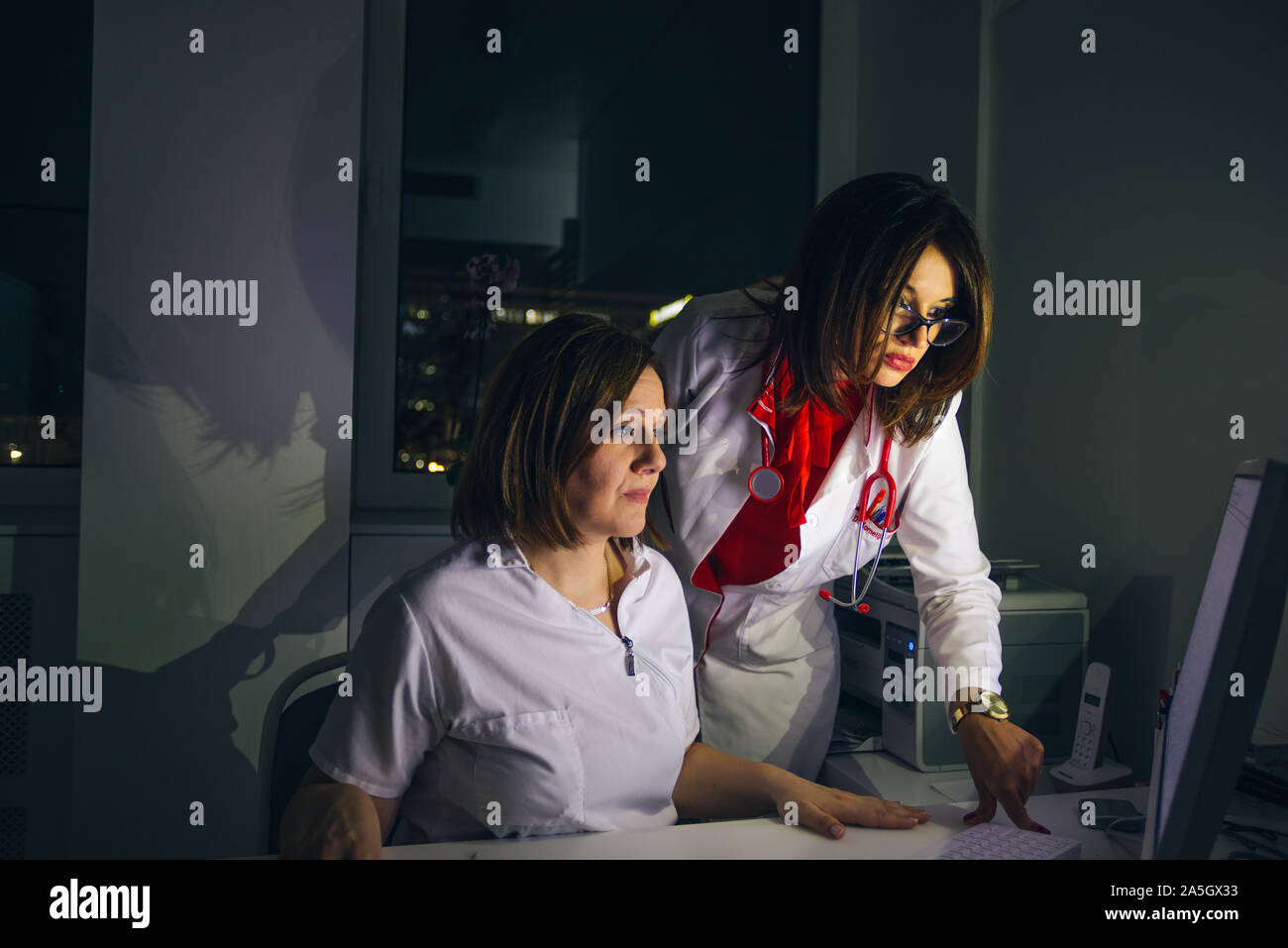 Female doctors ( medics ) work on a pc late at night Stock Photo - Alamy