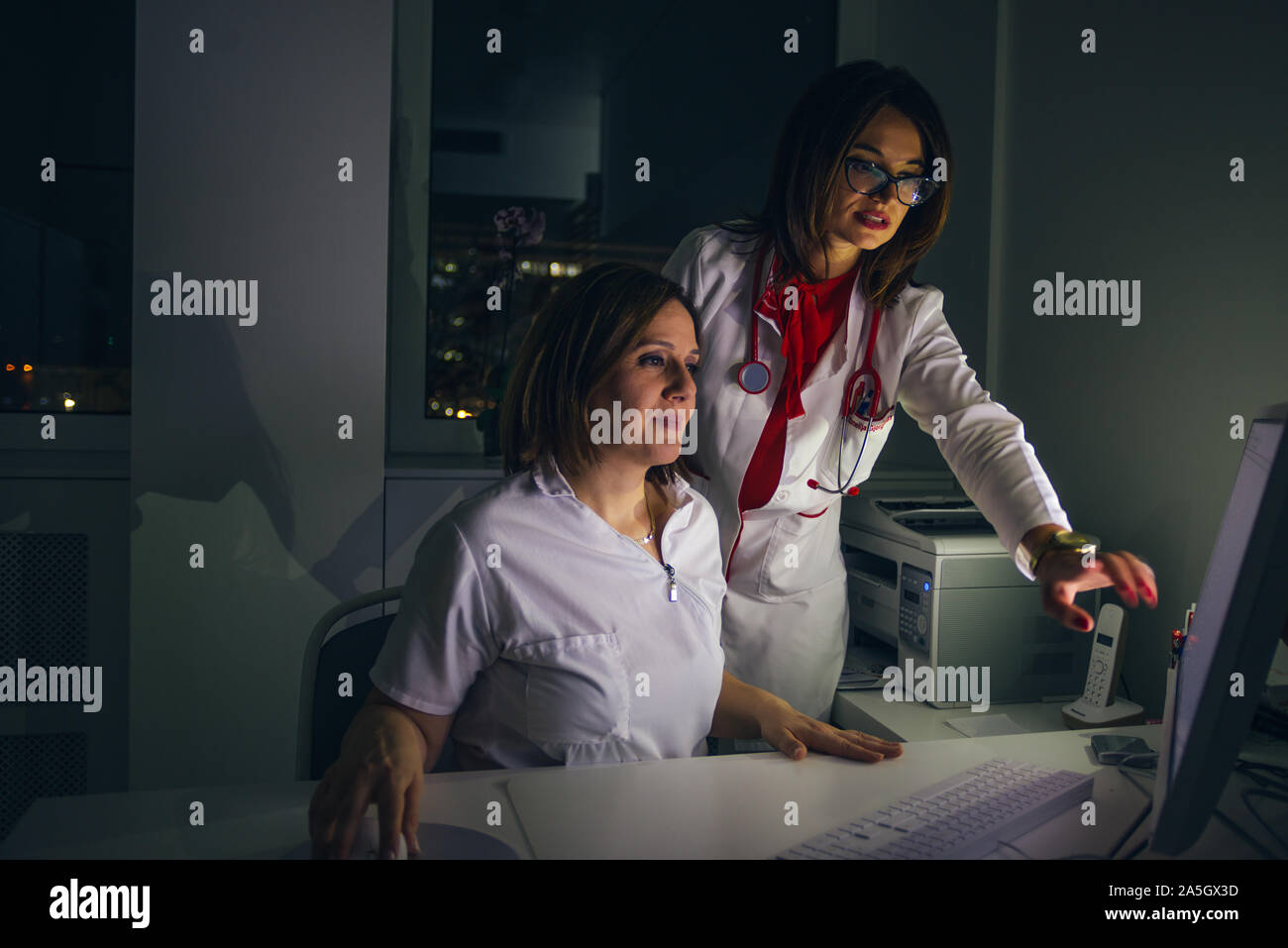 Female doctors ( medics ) work on a pc late at night Stock Photo - Alamy