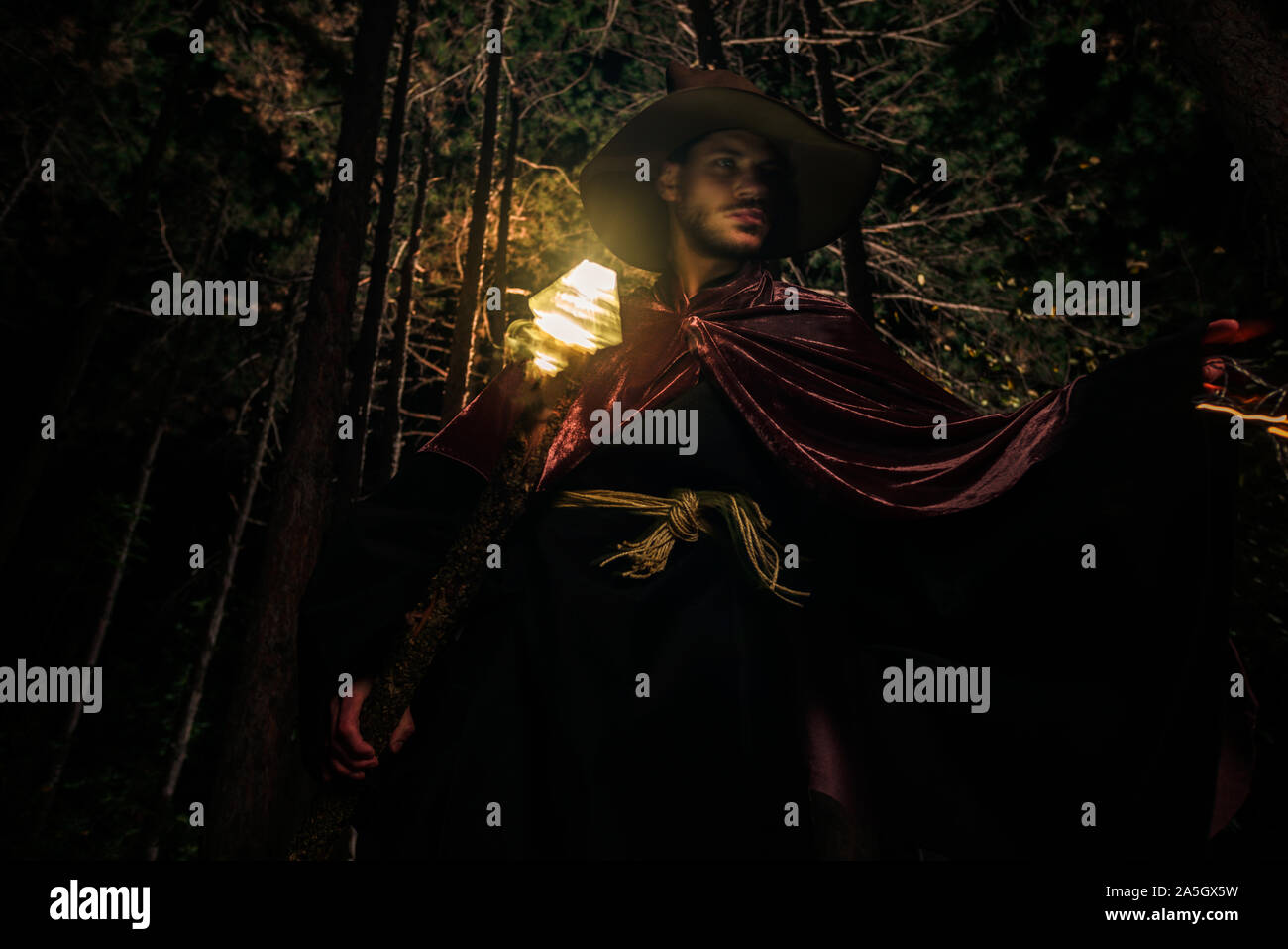 Cosplayer wearing wizard hat and clothes with a wooden glowing staff ...