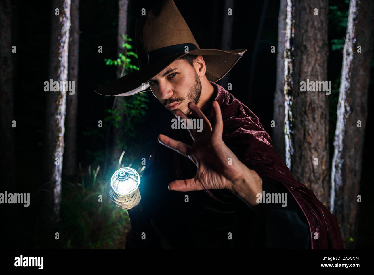 Wizard costume wearing guy with wooden staff standing between trees for ...