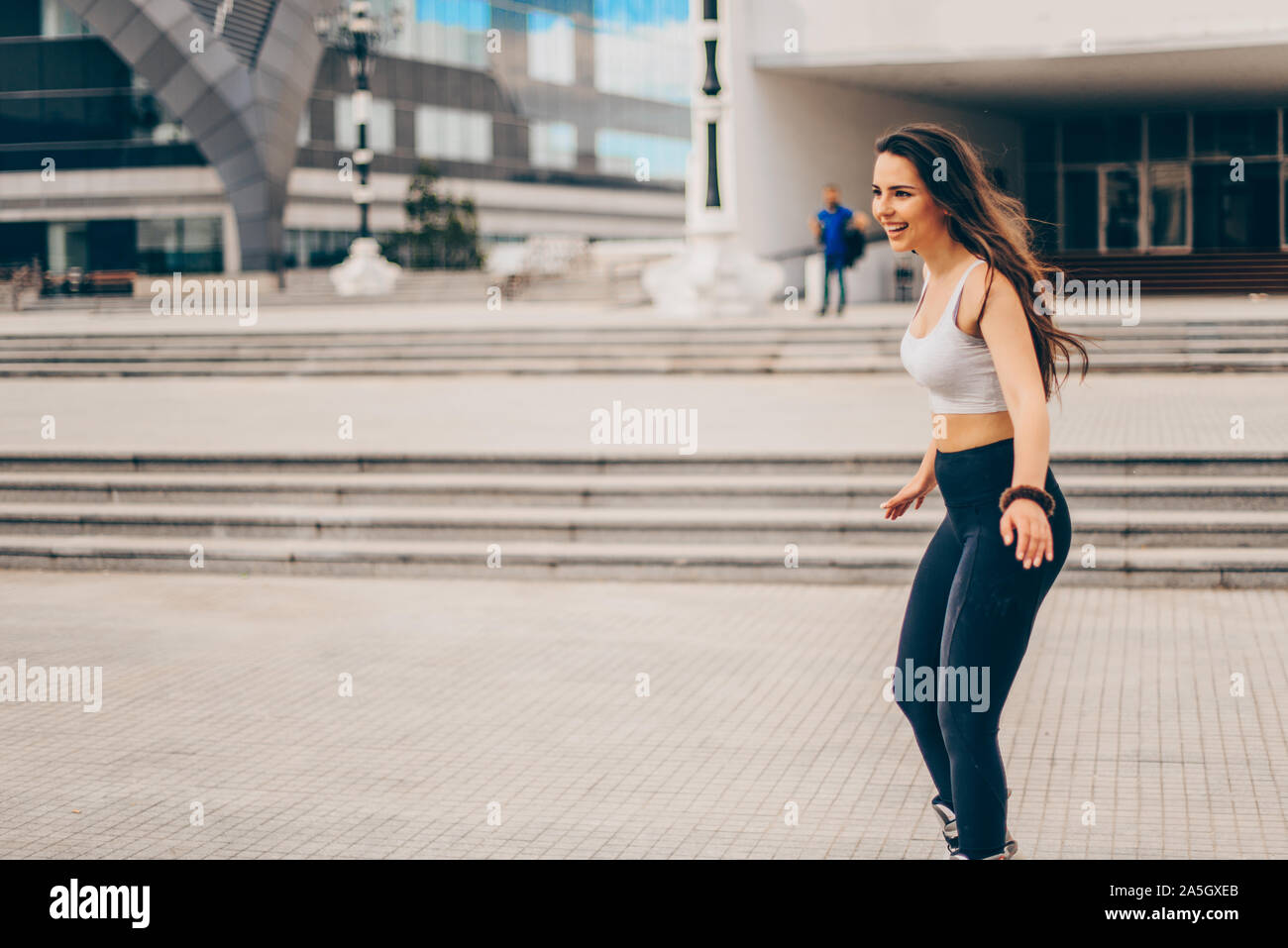 Gorgeous smiling girl is roller skating at city square Stock Photo - Alamy