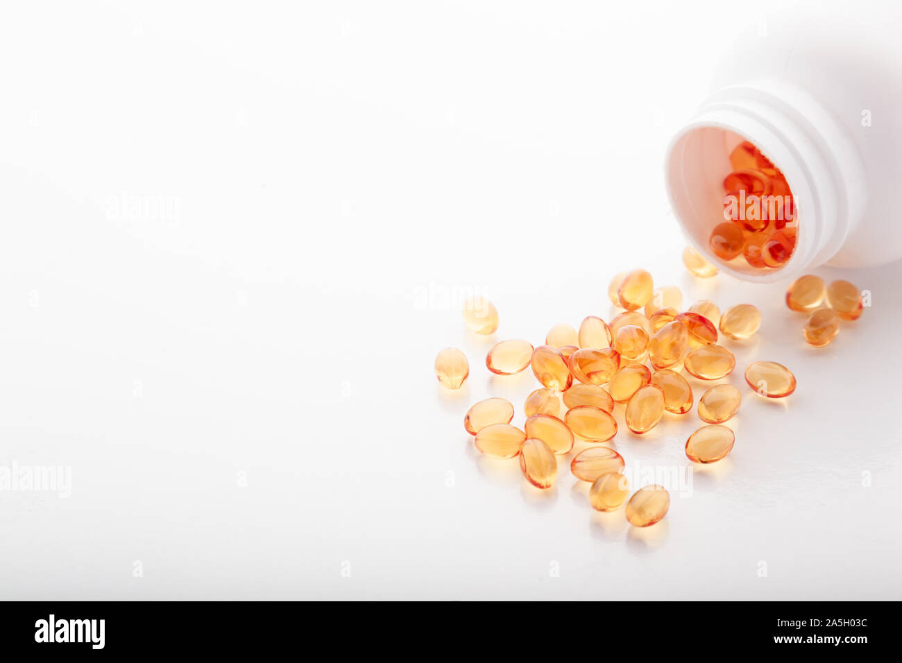 Top view of Gold fish oil scattered from pill bottle isolated for good ...